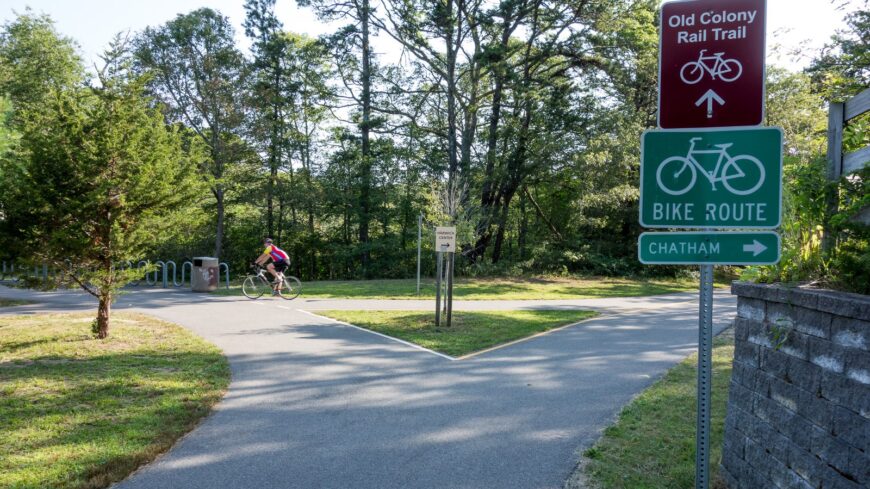 Cyclist riding near a bike-route sign used as an editorial ...